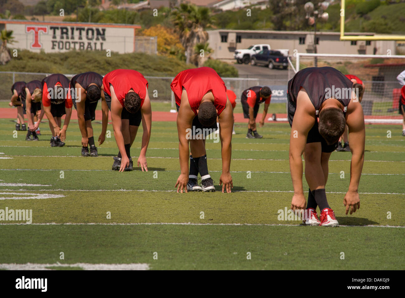 Multi-ethnic high school athletes limber up with flexibility exercises ...