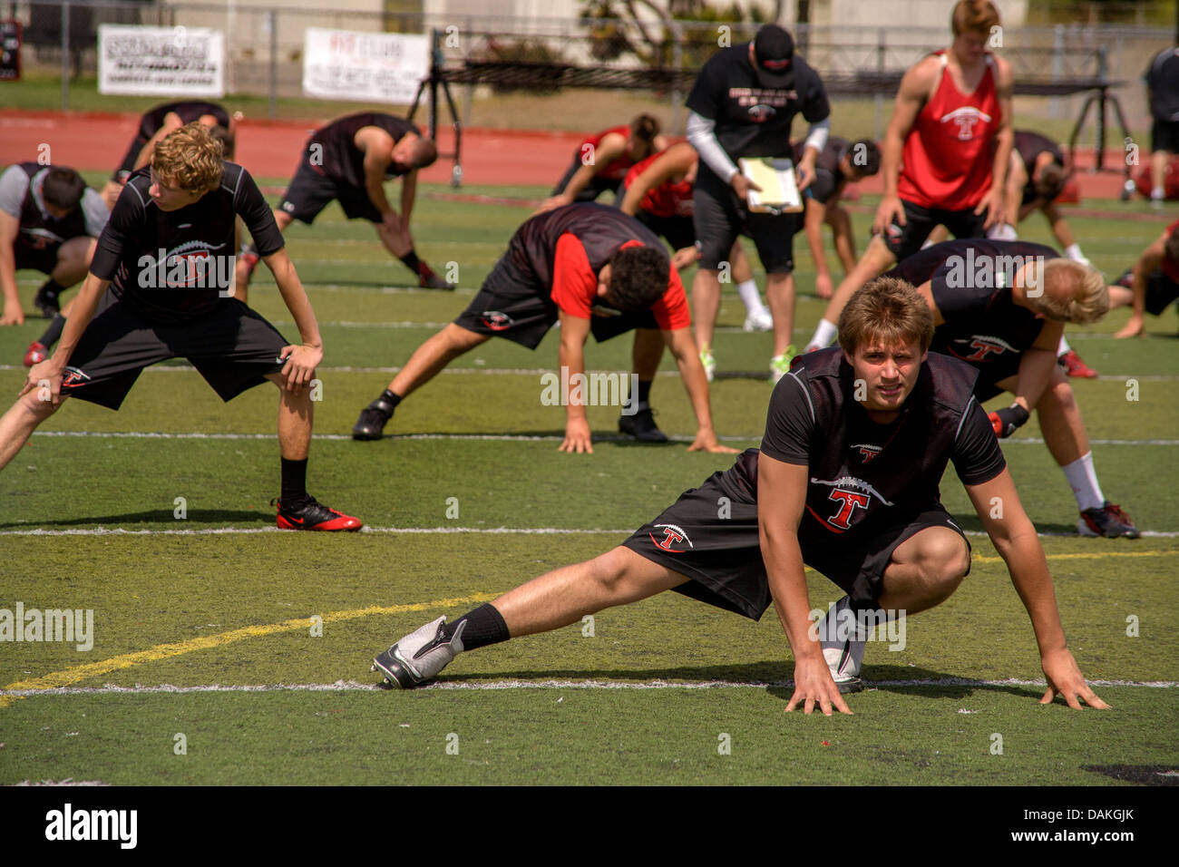 Multi-ethnic high school athletes limber up with flexibility exercises ...