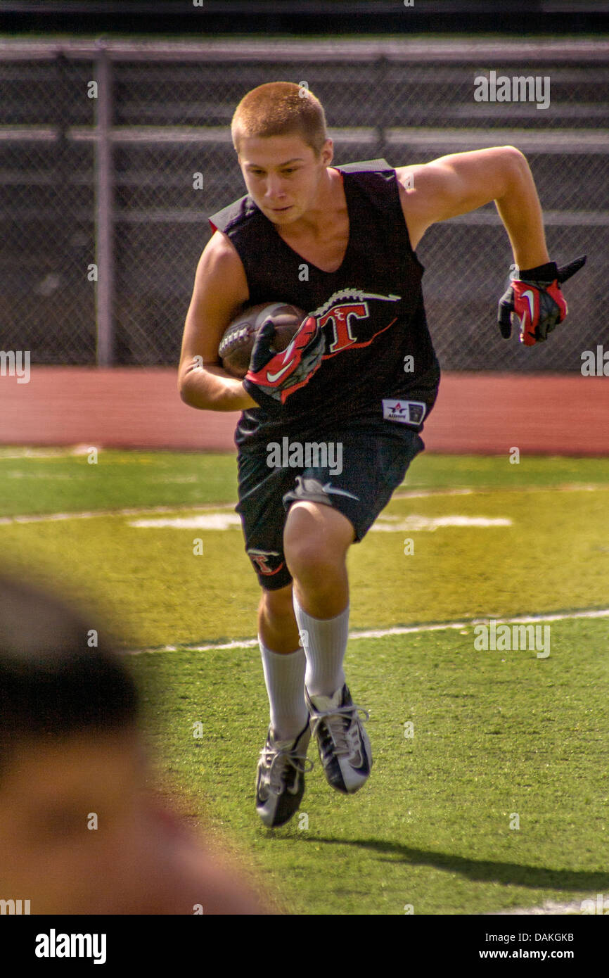 A muscular and determined high school athlete runs with the ball during ...