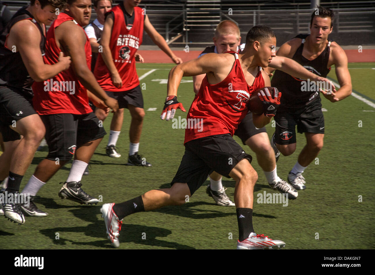 Carrying the ball, a high school athlete dodges tacklers while running ...