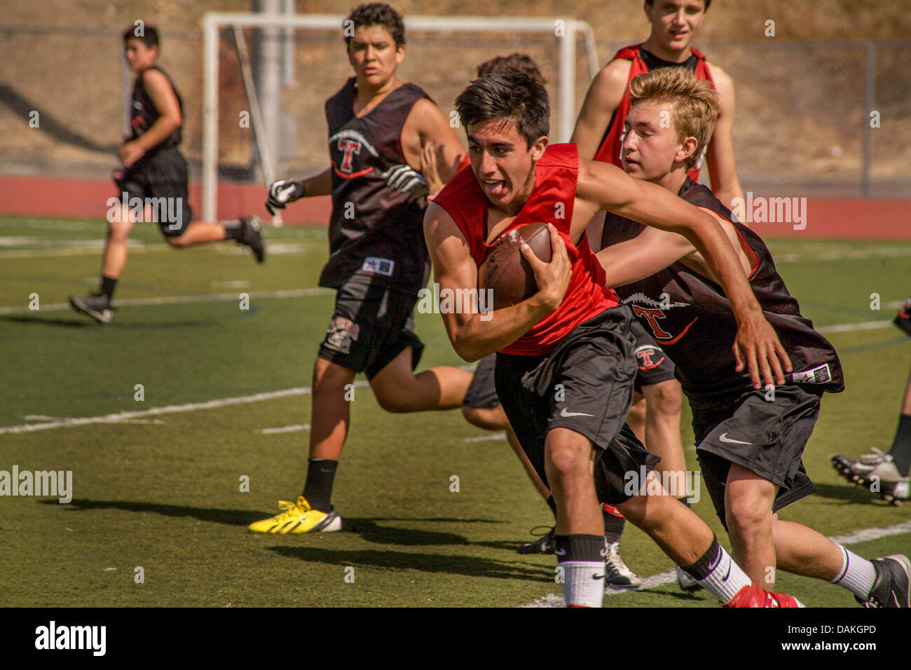 Carrying the ball, a high school athlete dodges tacklers while running ...