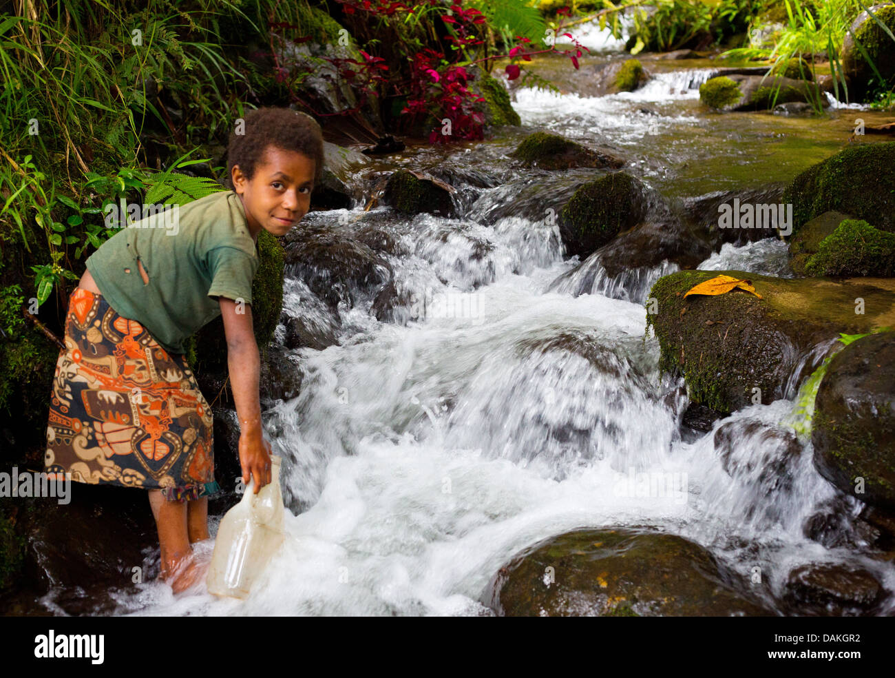 Young girl collecting water from a beautiful flowing stream in ...