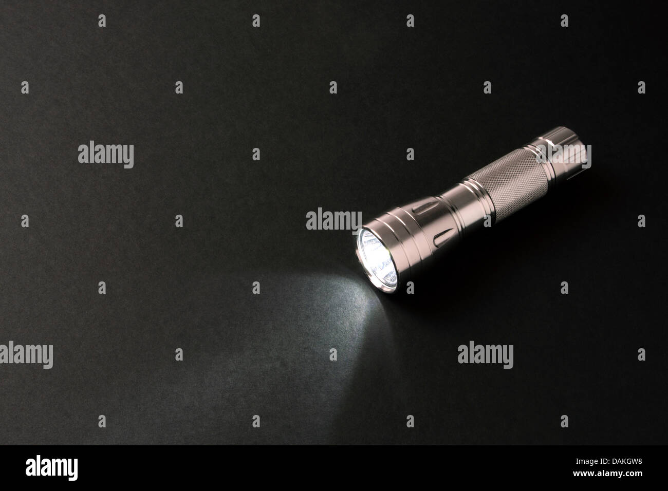 Flashlight lying on a dark gray background. Light is on Stock Photo - Alamy