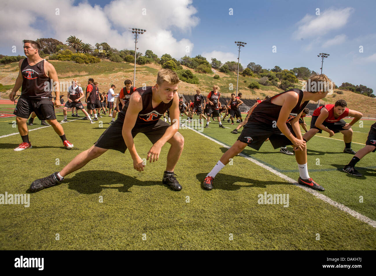 High school athletes limber up with flexibility exercises as they begin ...