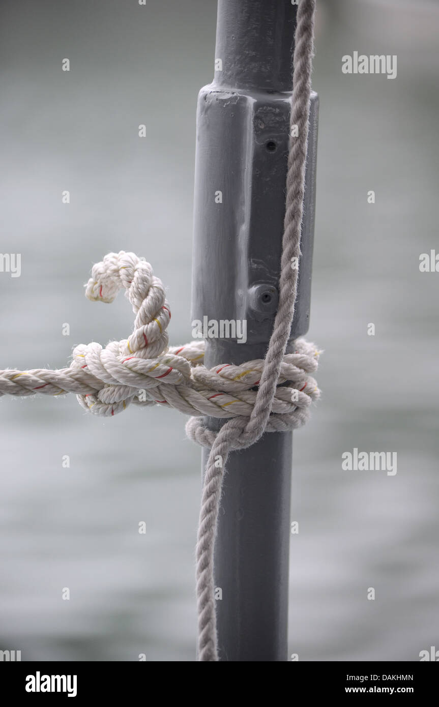 Rope tied off to a post using boating knots blurred ocean water ...