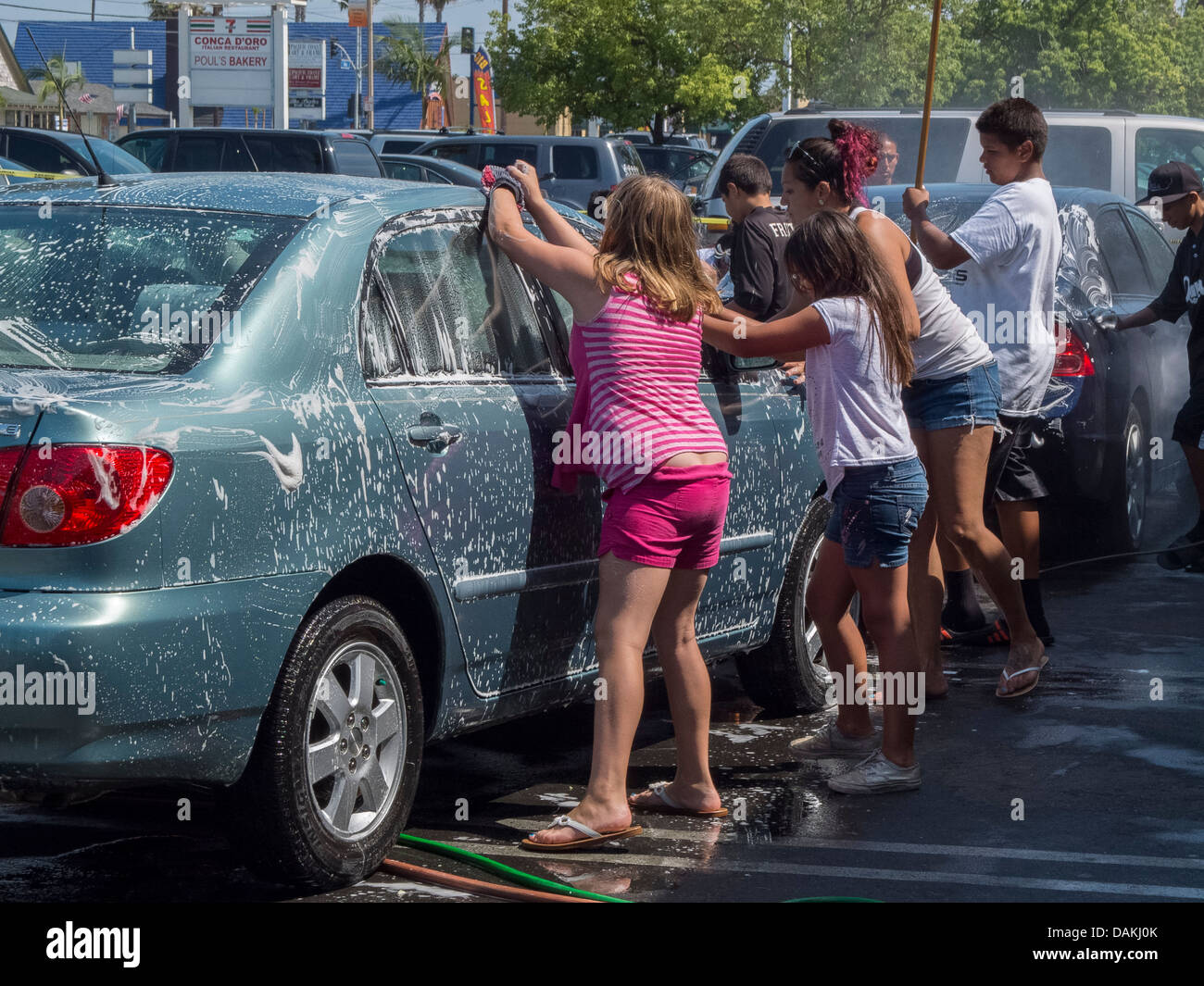 Multiethnic local children assist at a fund-raising charity car wash in ...