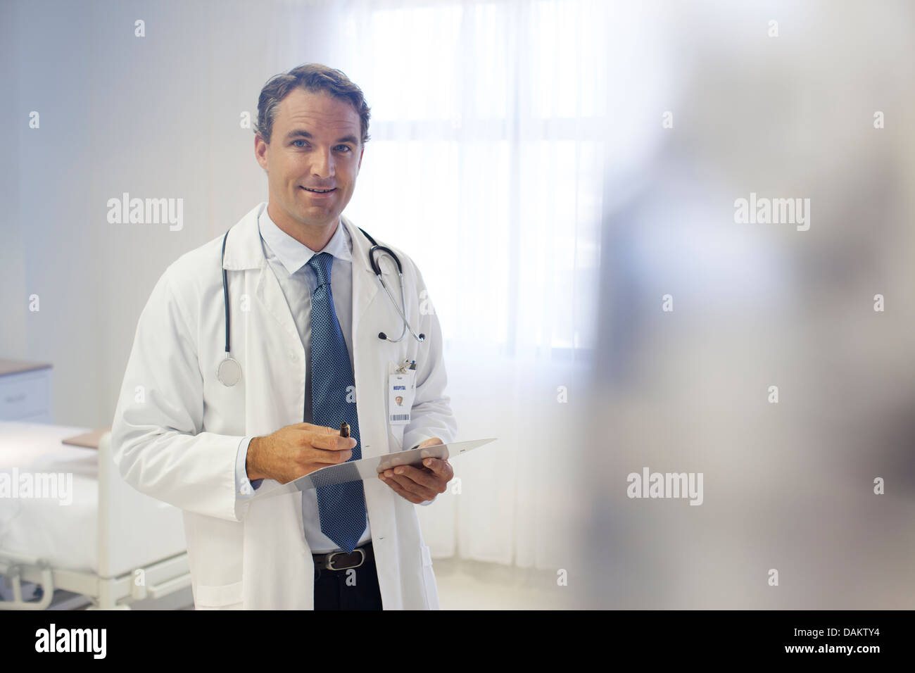 Doctor reading clipboard in hospital room Stock Photo - Alamy