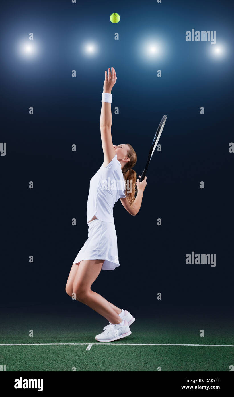 Tennis player serving ball on court Stock Photo - Alamy