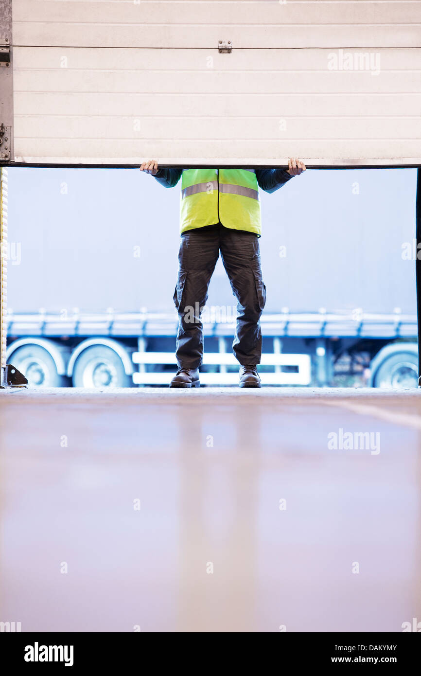 Worker lifting door in warehouse Stock Photo - Alamy