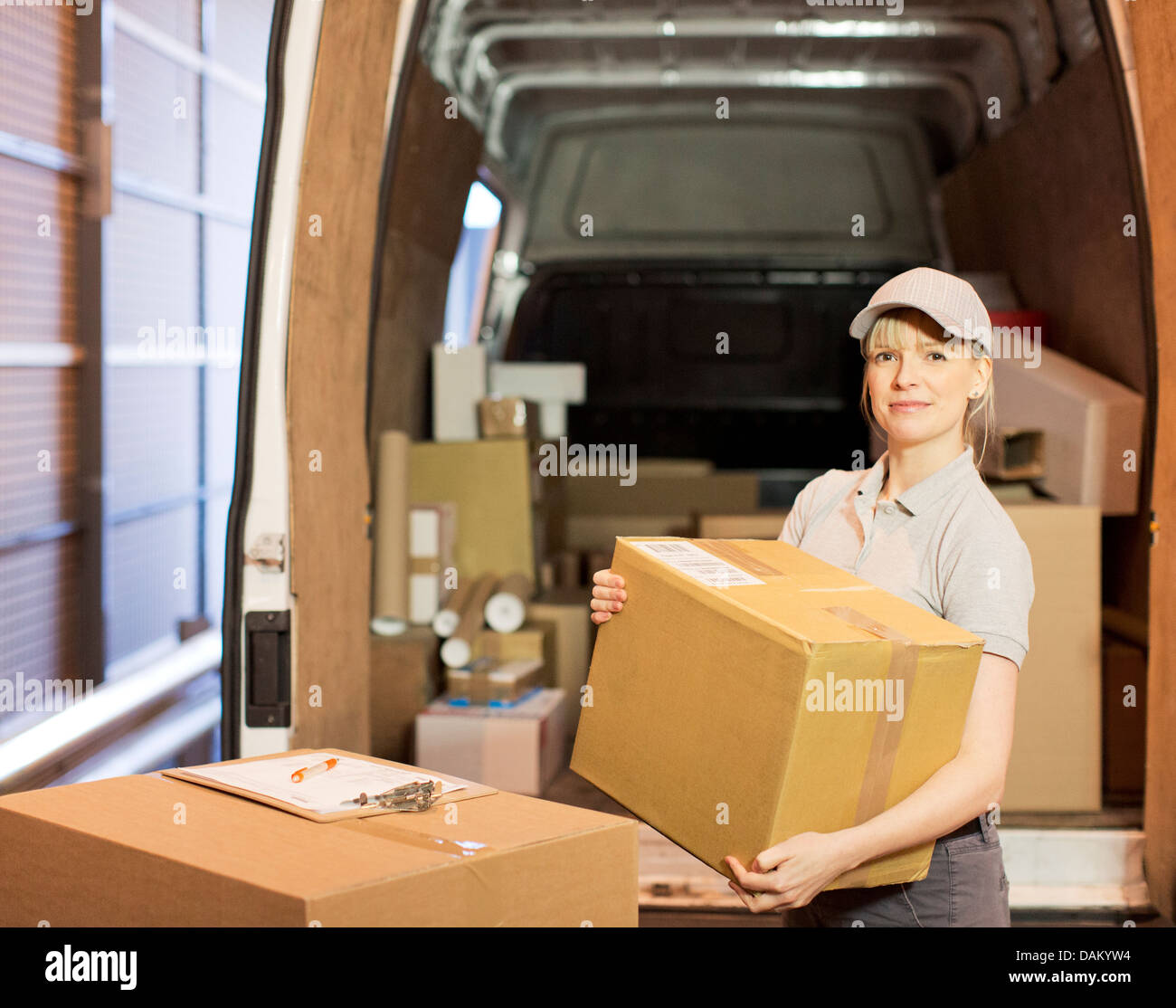 Delivery girl unloading boxes from van Stock Photo - Alamy