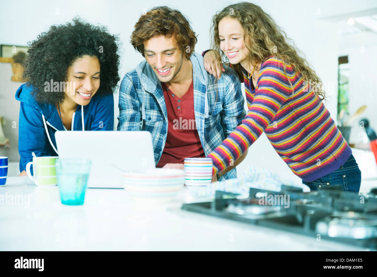 Friends using laptop together in kitchen Stock Photo - Alamy