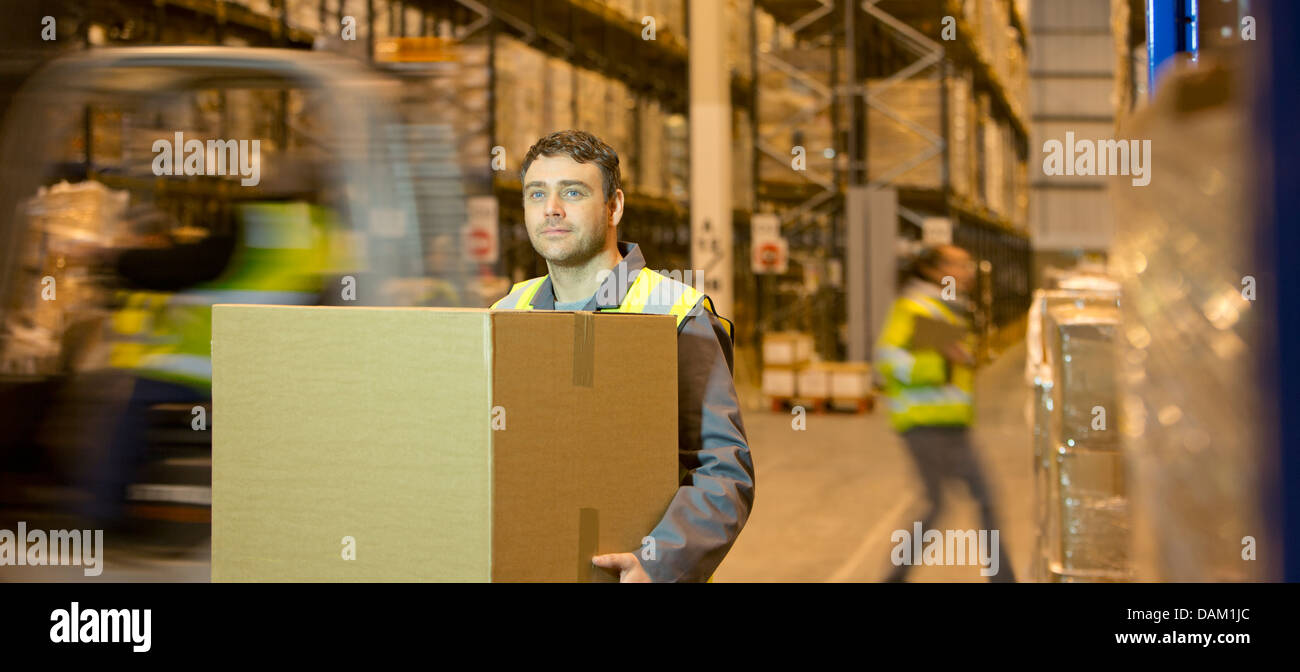 Worker carrying box in warehouse Stock Photo - Alamy