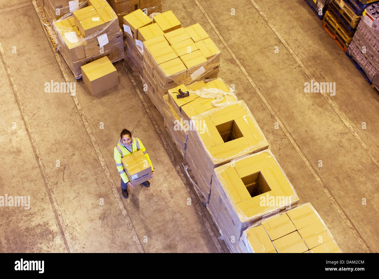 Worker carrying box in warehouse Stock Photo - Alamy