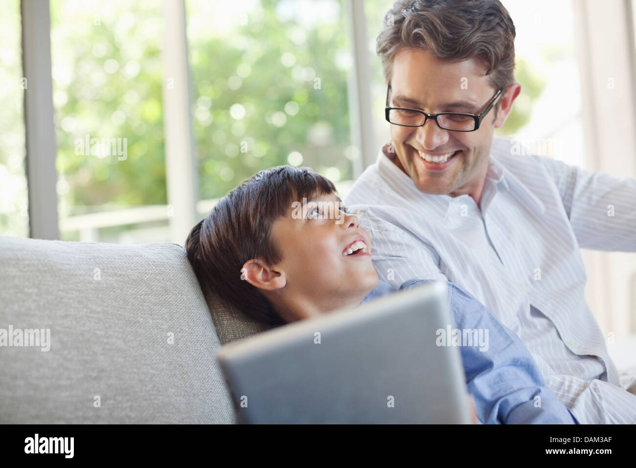 Father and son using tablet computer on sofa Stock Photo - Alamy