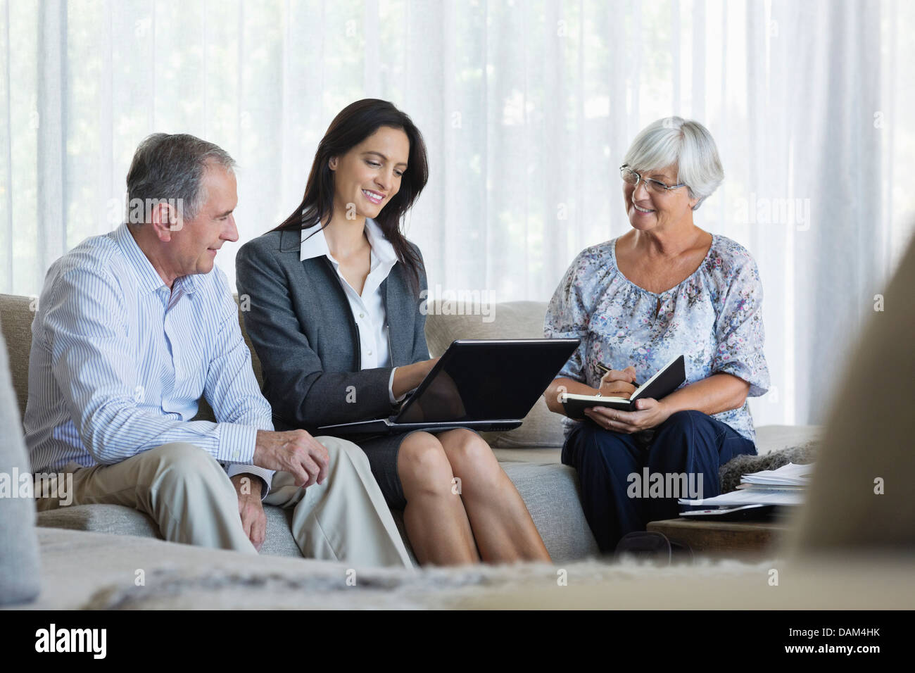 Financial advisor talking to couple on sofa Stock Photo - Alamy