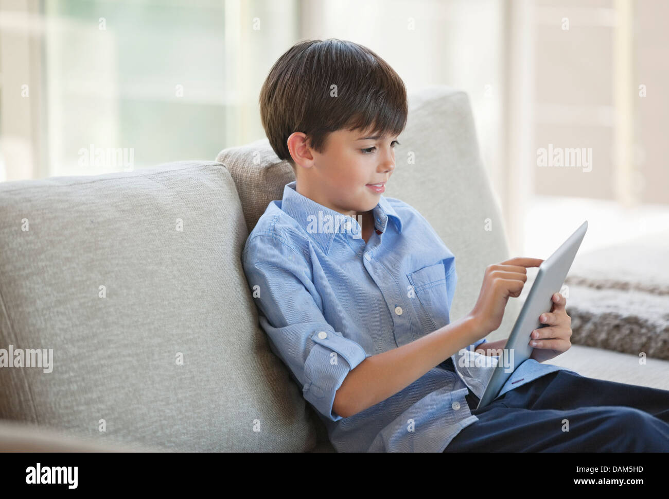 Boy using tablet computer on sofa Stock Photo - Alamy