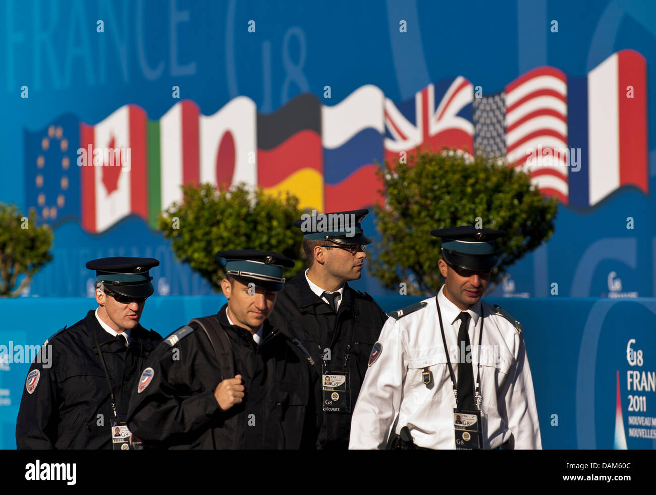 Police officers walk past a poster of the G8 summit in Deauville ...
