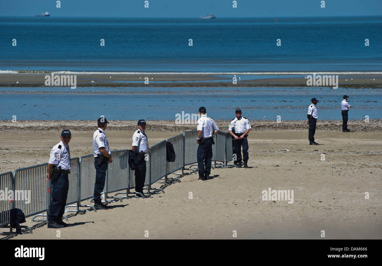 Police officers secure an area of the beach in front of the premises of ...