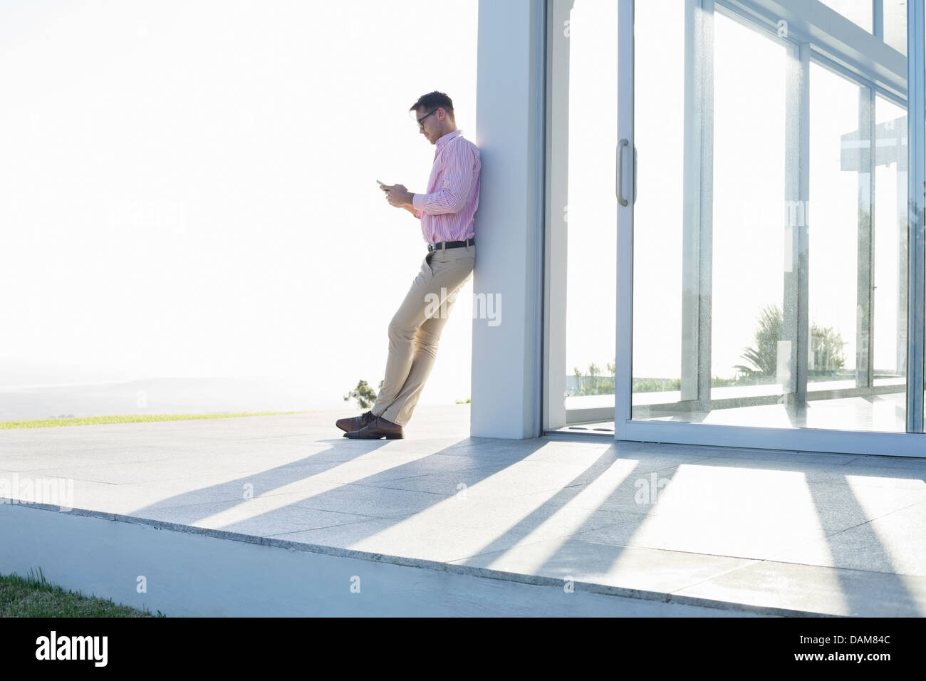 Businessman using cell phone outside office Stock Photo - Alamy