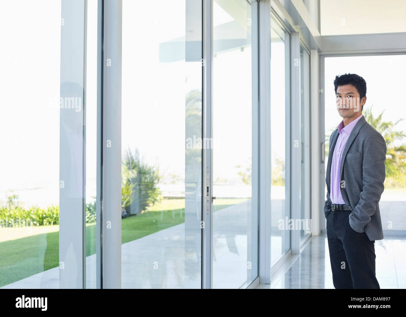 Businessman standing at office window Stock Photo - Alamy