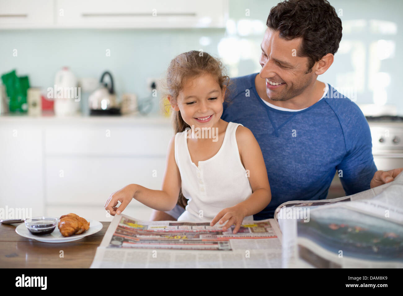 Father and daughter reading newspaper at breakfast Stock Photo - Alamy