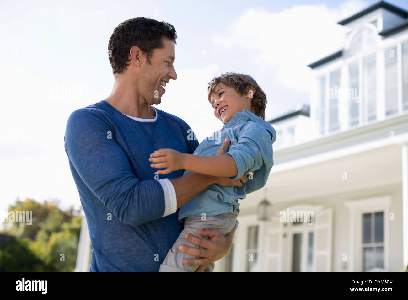 Father and son smiling outside house Stock Photo - Alamy
