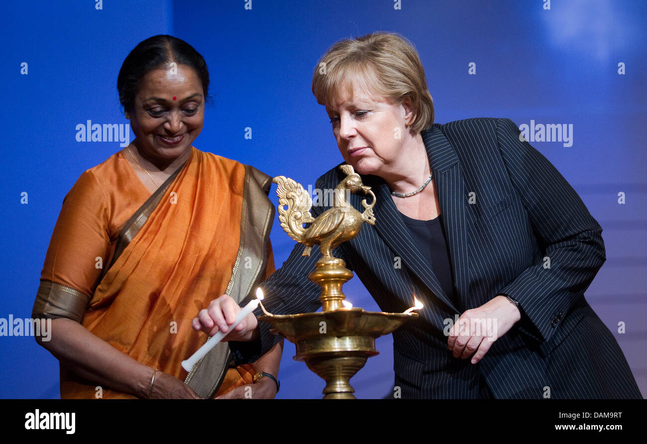 German Federal Chancellor Angela Merkel (R) lights an oil lamp next to ...