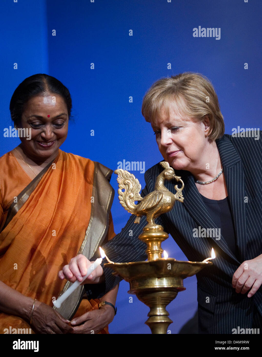 German Federal Chancellor Angela Merkel (R) lights an oil lamp next to ...