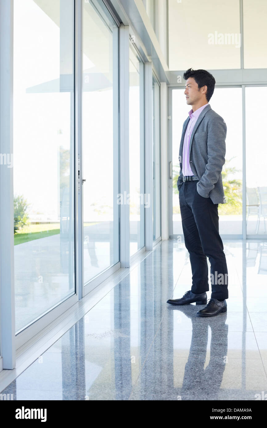 Businessman standing at office window Stock Photo - Alamy