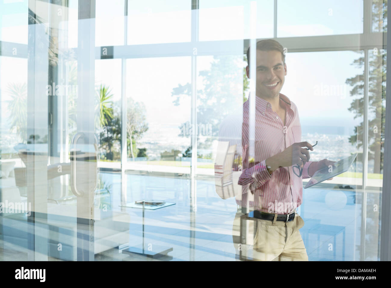 Businessman smiling at office window Stock Photo - Alamy