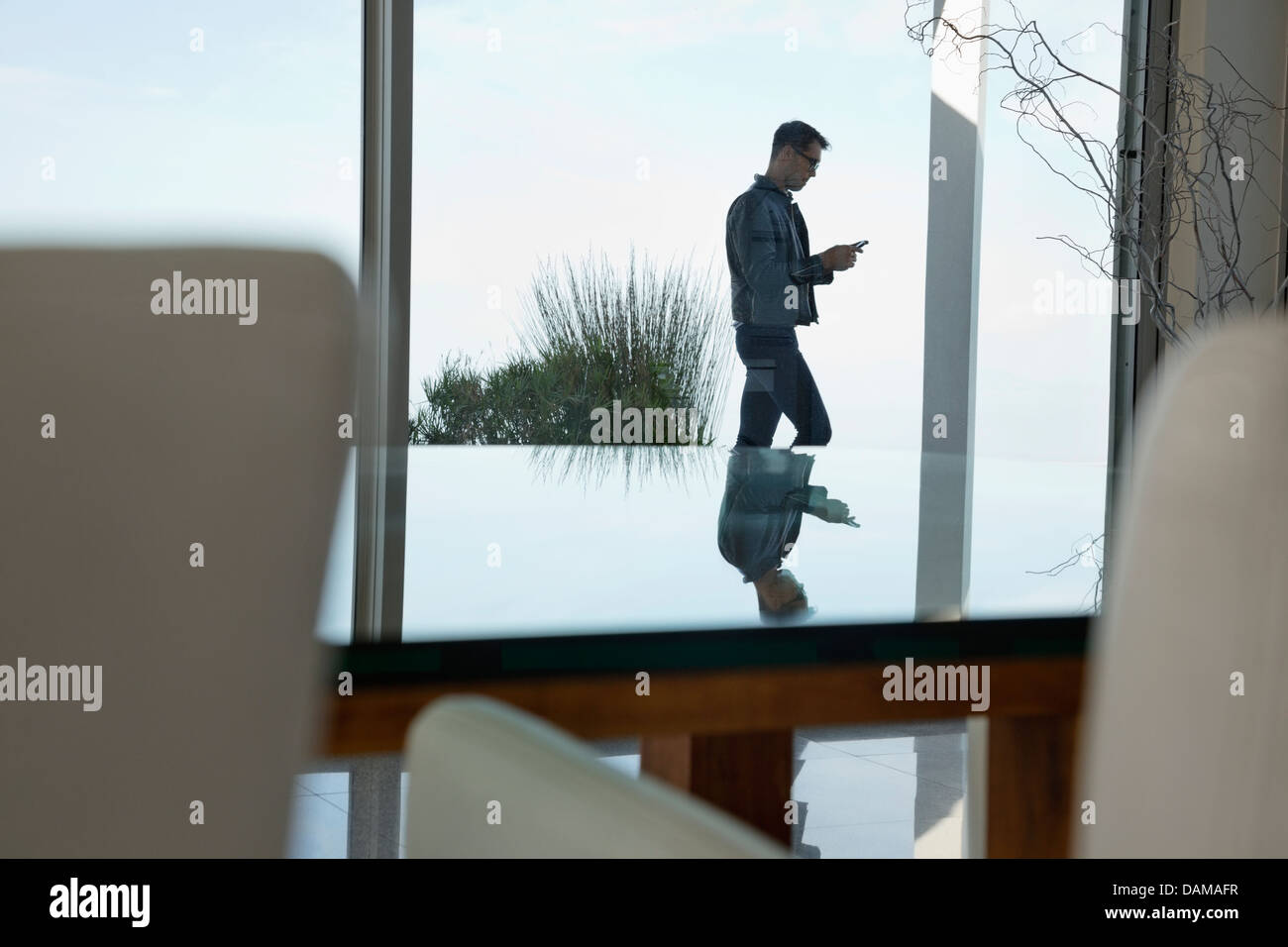 Businessman using cell phone at office window Stock Photo - Alamy