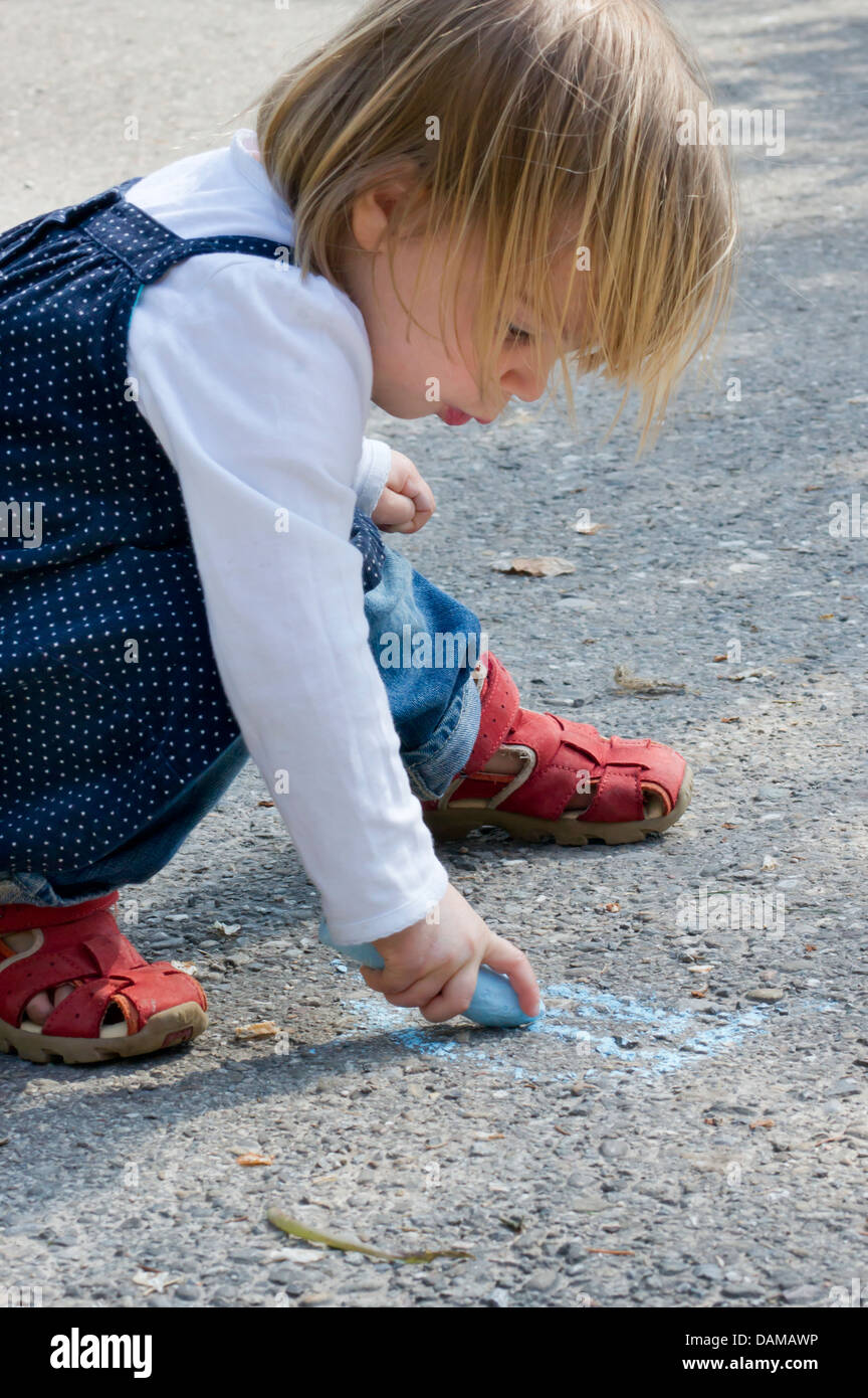 Germany, Little girl using chalk Stock Photo - Alamy