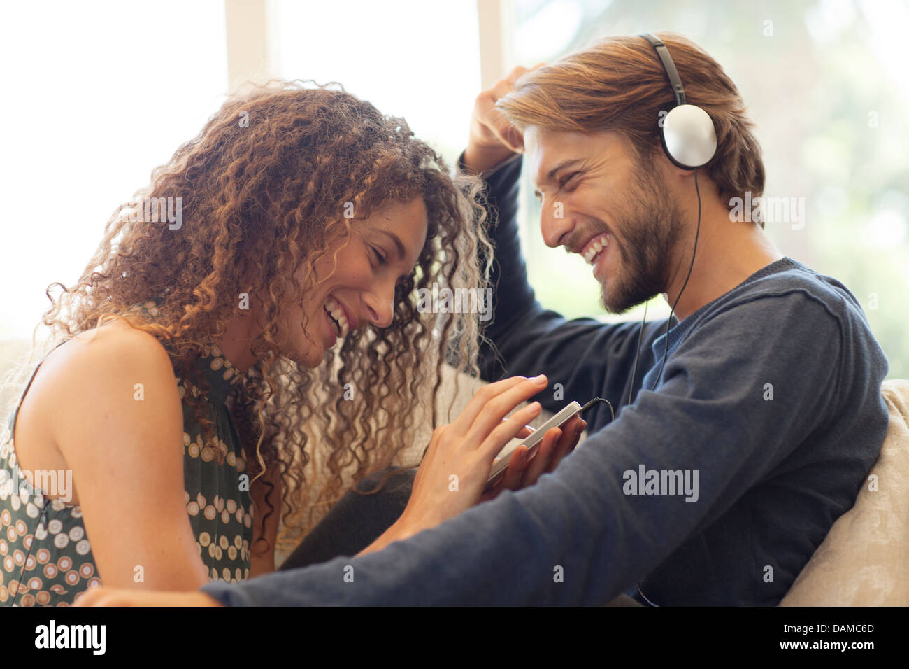 Couple listening to headphones on sofa Stock Photo - Alamy