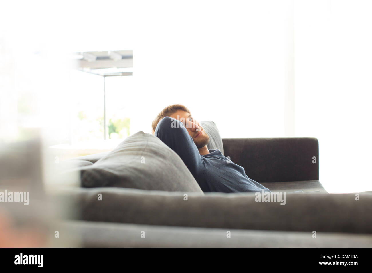 Smiling man relaxing on sofa Stock Photo - Alamy