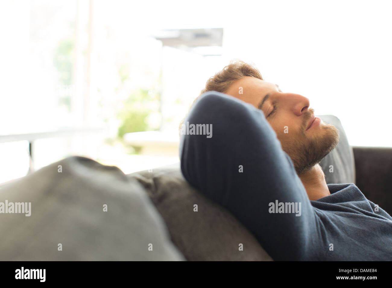 Man relaxing on sofa Stock Photo - Alamy