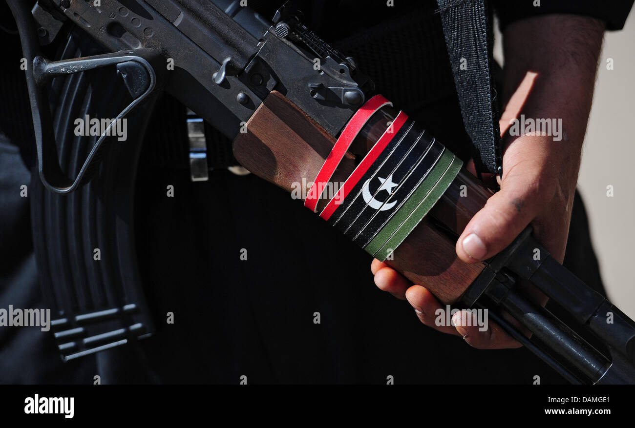 A guard holds a Kalashnikov with the Libyan flag on it at an airport in ...