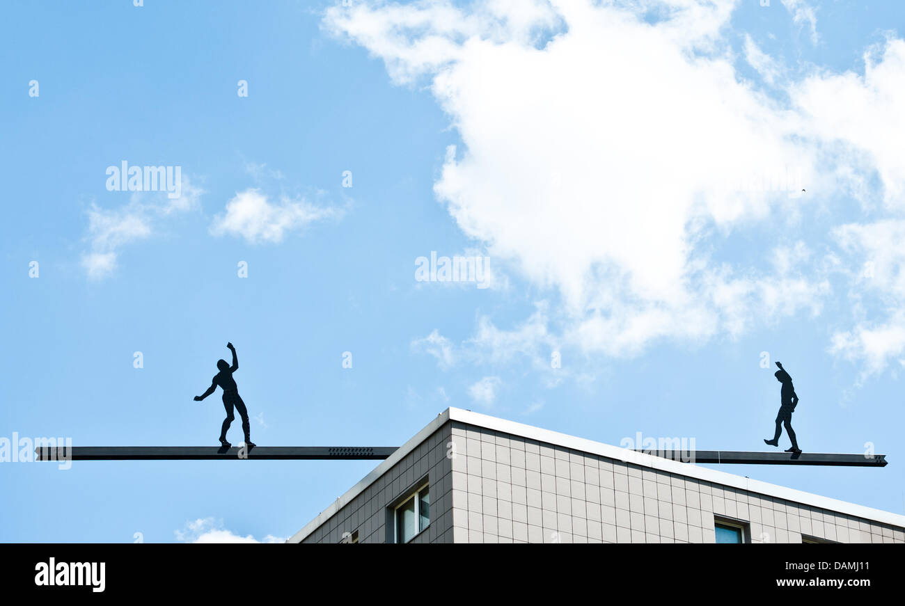Two figures balance on a bar attached to a highriser in front of a ...