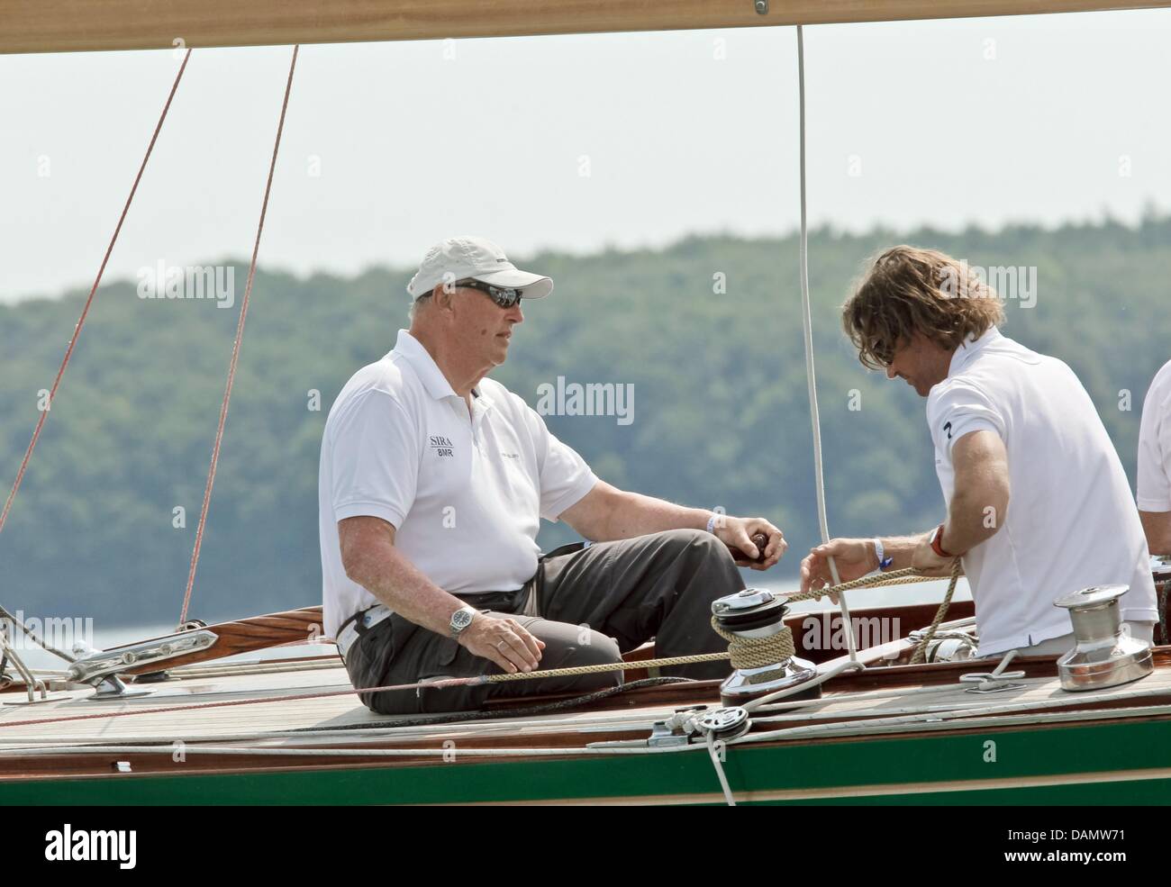 King Harald V of Norway (L) sits at the helm of his boat Sira as ...