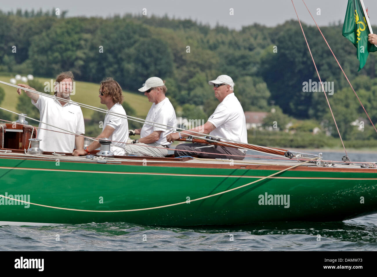 King Harald V of Norway (R) sits at the helm of his boat Sira as ...