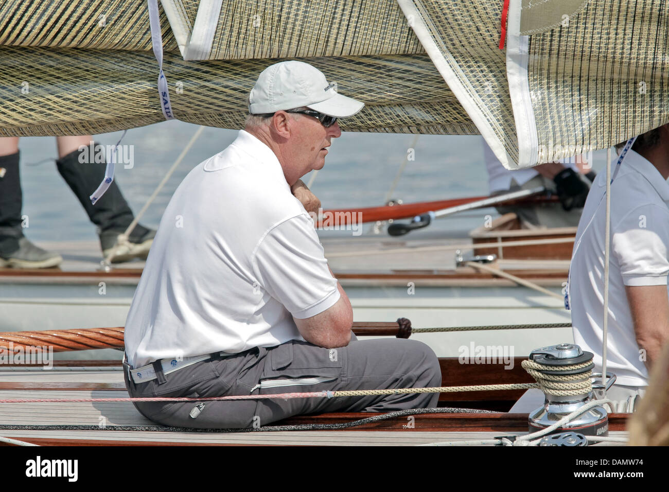 King Harald V of Norway (L) sits at the helm of his boat Sira as ...