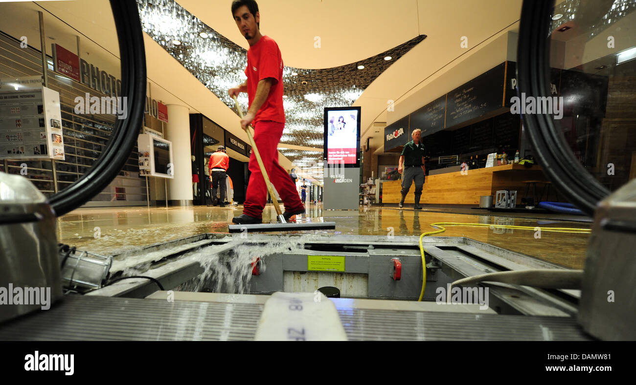 A man mops water into a drain after heavy rains caused flooding in the ...