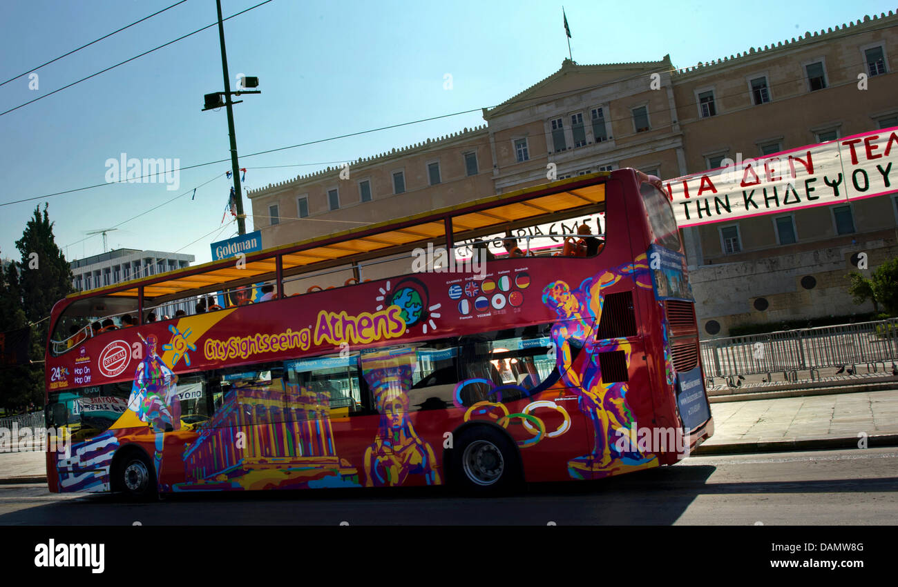 A "City Sightseeing" bus with tourists drives in front of the Greek ...