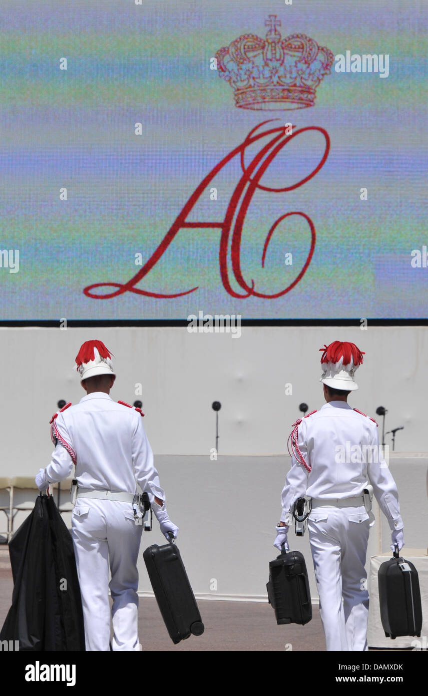 Two royal guards carry bags over the palace square under a big video ...