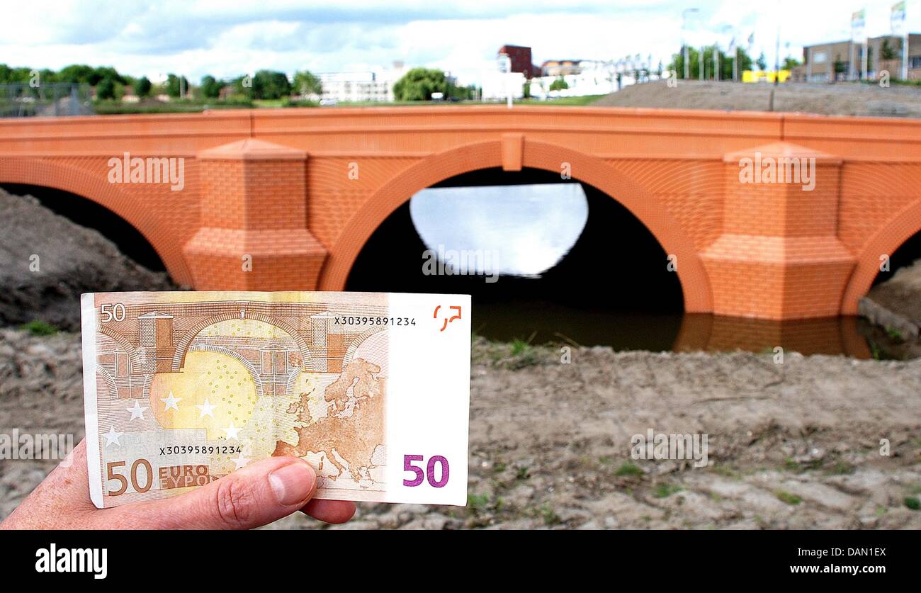 A man holds a fifty-euro-bill in front of a currently constructed ...