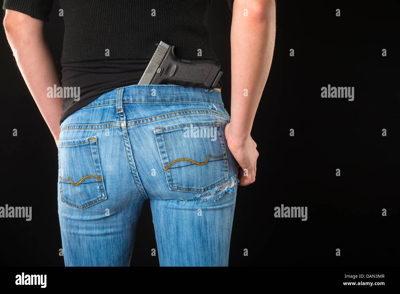 Young woman with handgun standing against black background Stock Photo ...