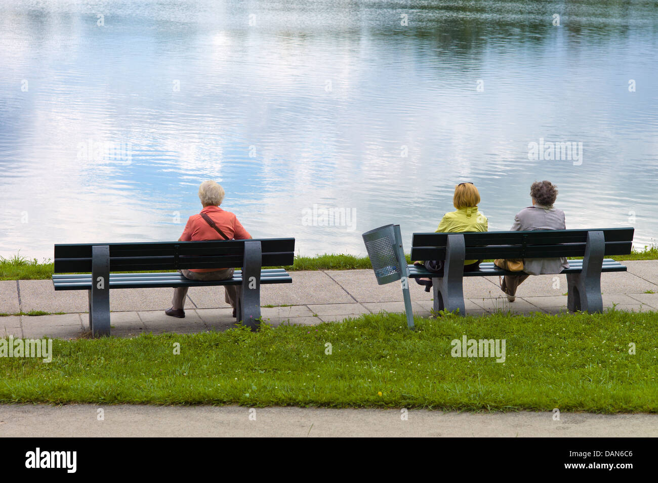 Austria, Upper Austria, Linz, People sitting on bench at Lake Pichling ...