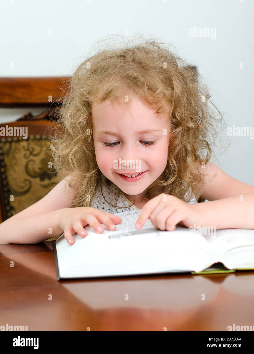 Cute little smiling girl reading a book Stock Photo - Alamy