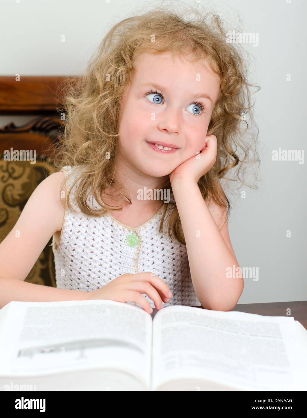 Cute little smiling girl reading a book Stock Photo - Alamy