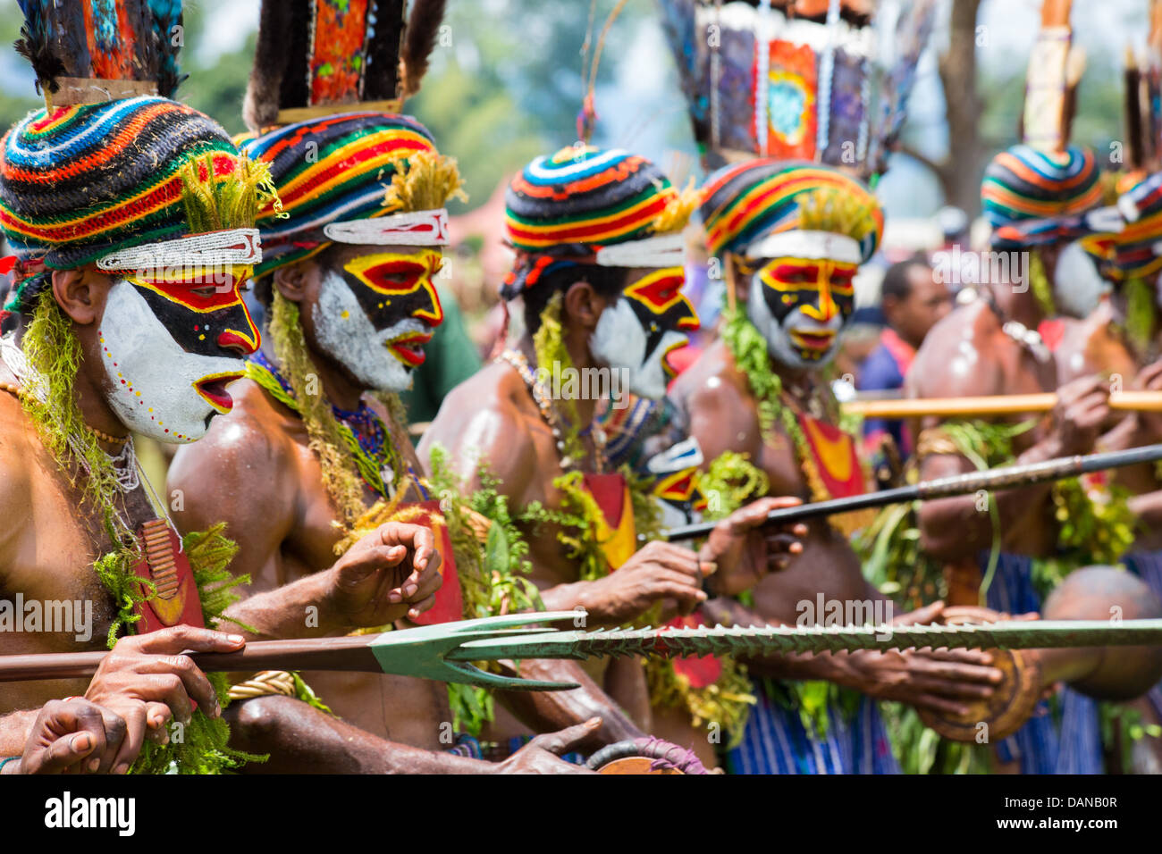 Men with their faces painted with tribal markings, performing a ...