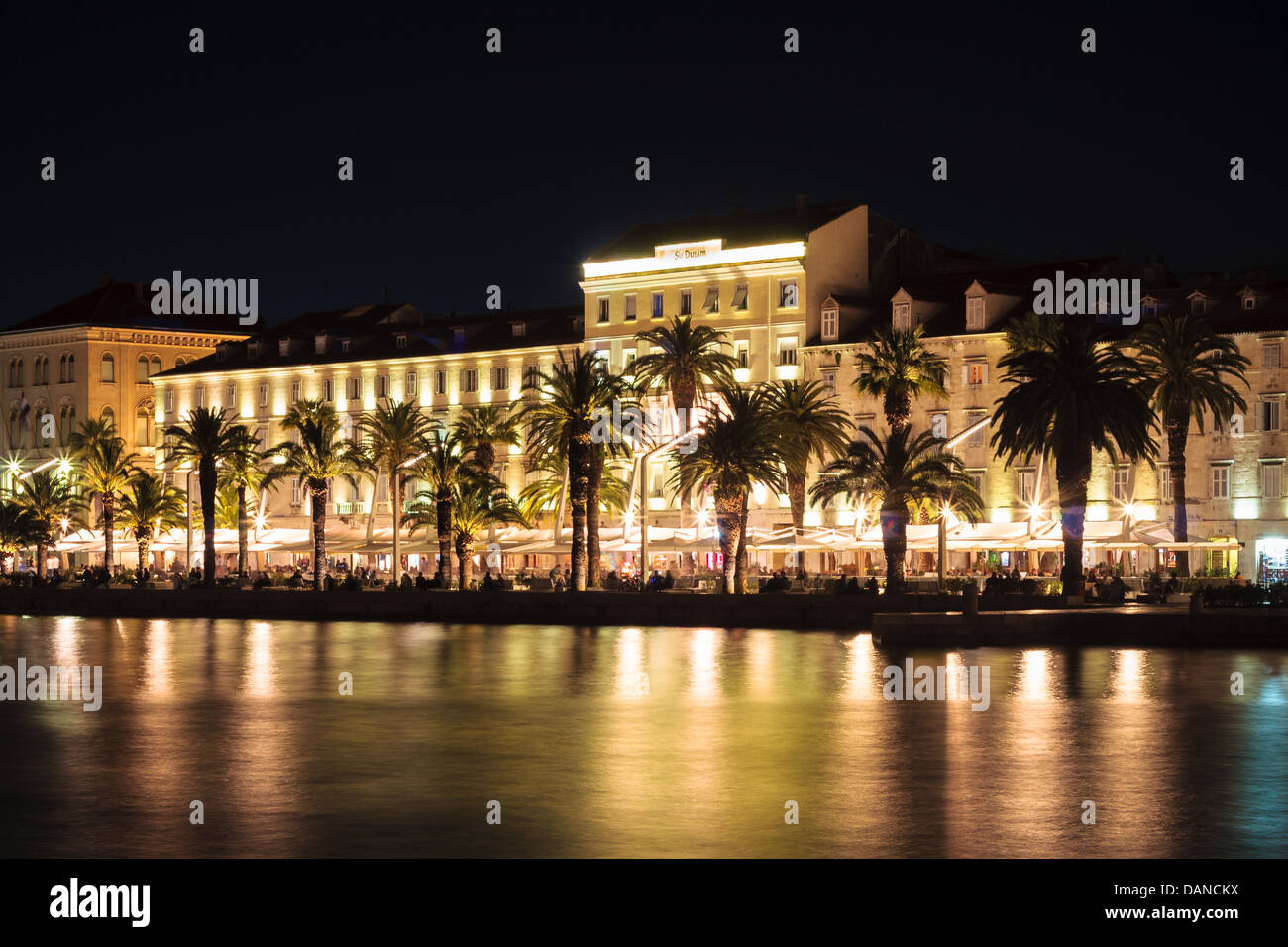 Palm trees lining the waterfront of Split Riva in Croatia are reflected ...